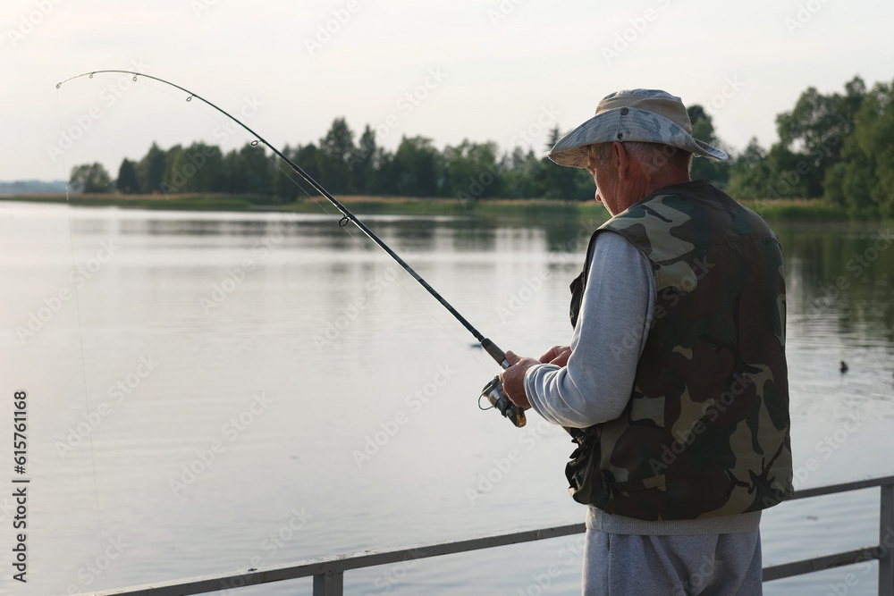 Old man fishing. Senior gray haired fisherman throws a spinning from ...