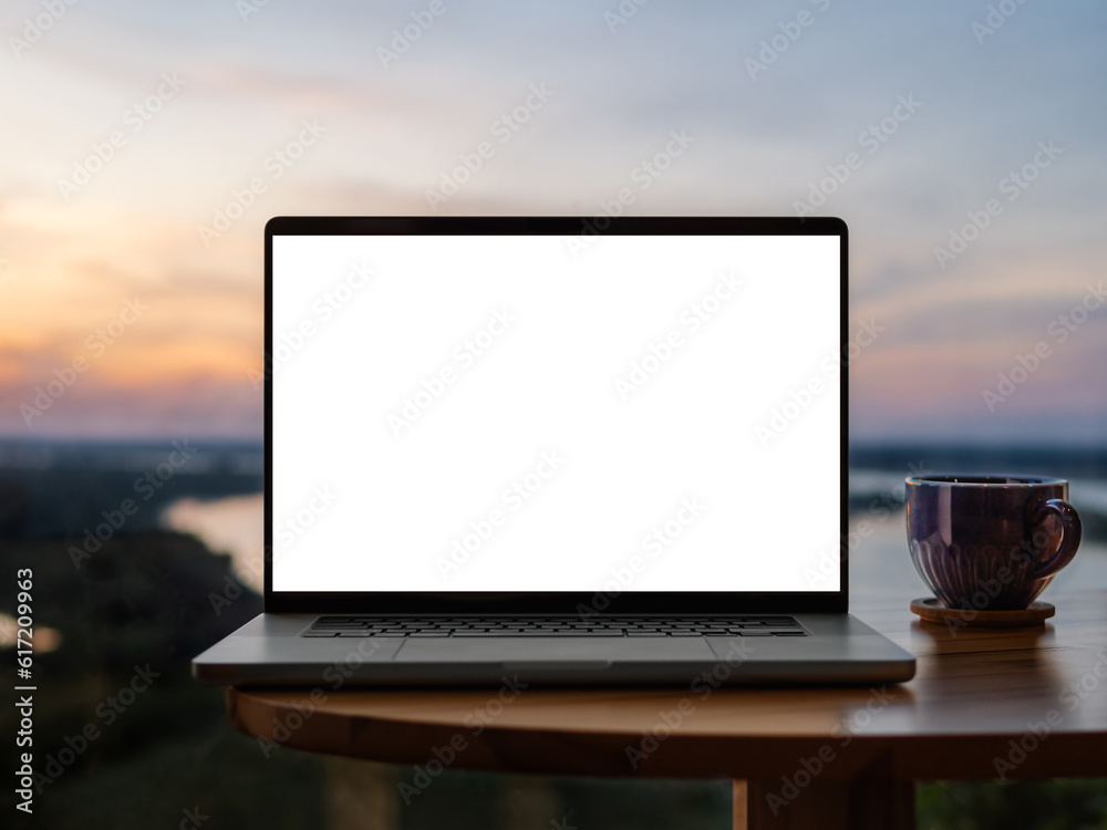 Laptop blank screen on wood table with amazing sunset sky over river ...