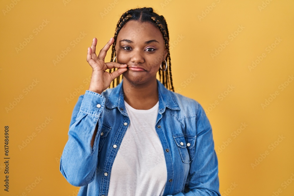 African american woman with braids standing over yellow background ...