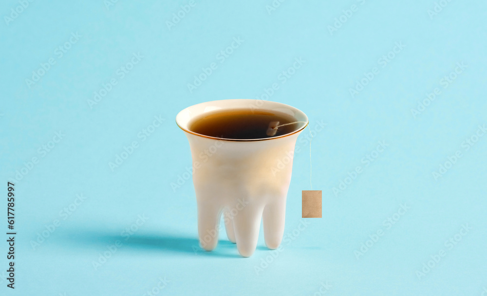 Art collage of cup of tea and model of human tooth. Teeth staining with ...