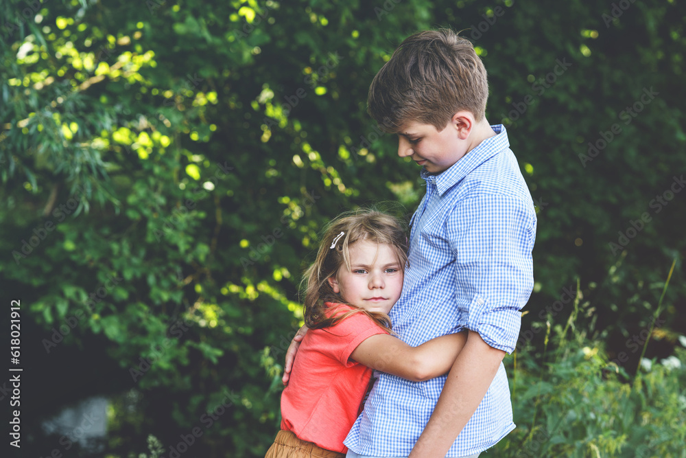 An upset little girl finds comfort in the embrace of her caring teenage ...