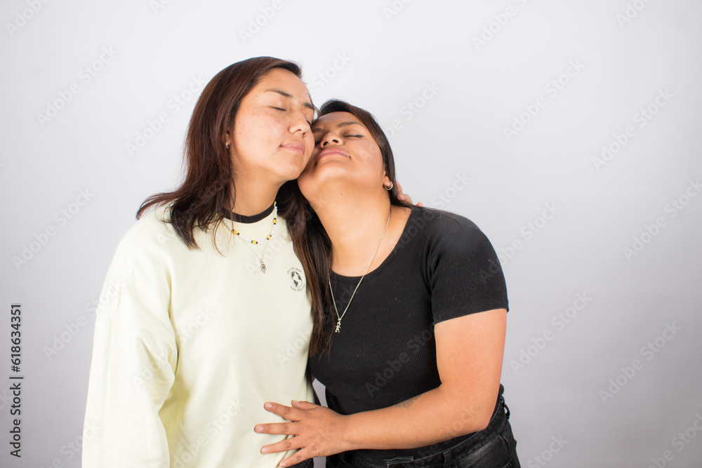 photograph of a happy female couple embracing on a light studio ...