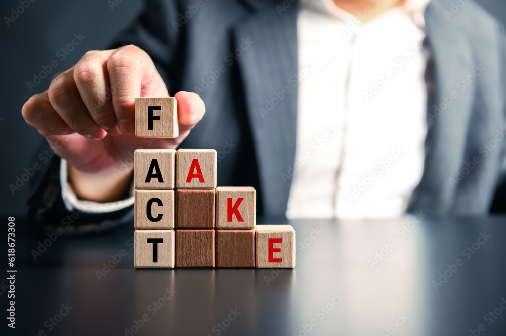 Businessman placing wooden blocks with words FACT and FAKE on black ...