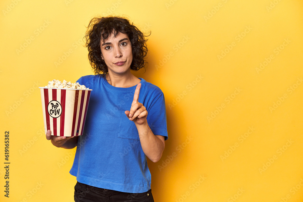 Curly-haired woman with popcorn for movie, studio showing number one ...