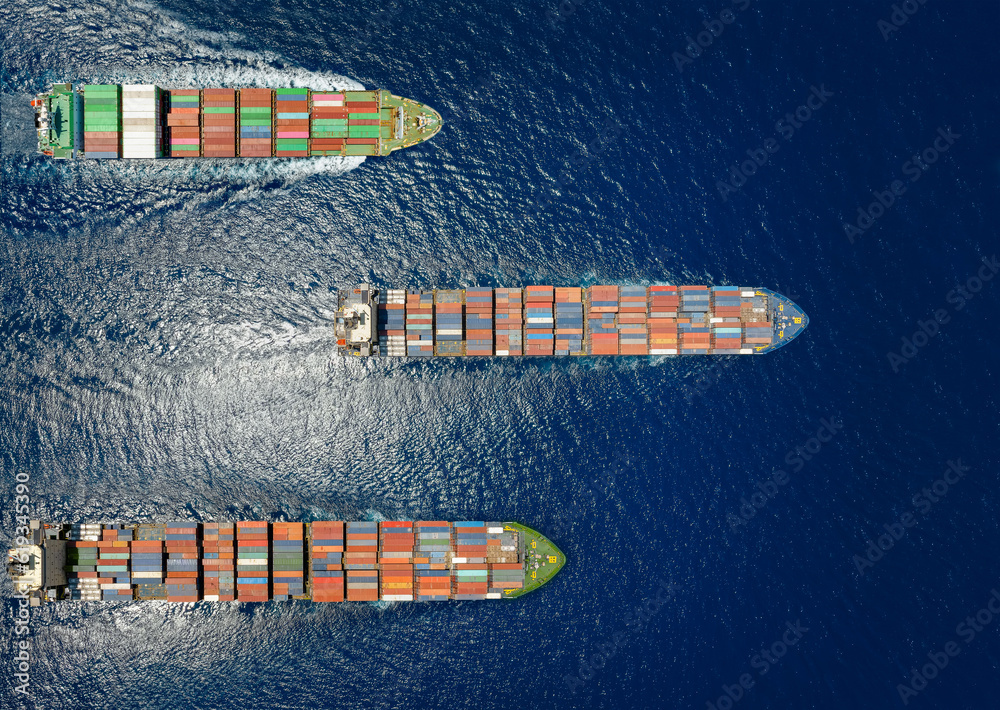 High aerial top down view of three container cargo ships in motion over ...