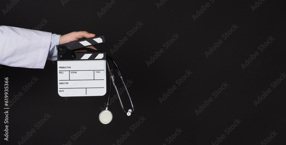 Doctor's hand holding stethoscope and clapper board on black background ...