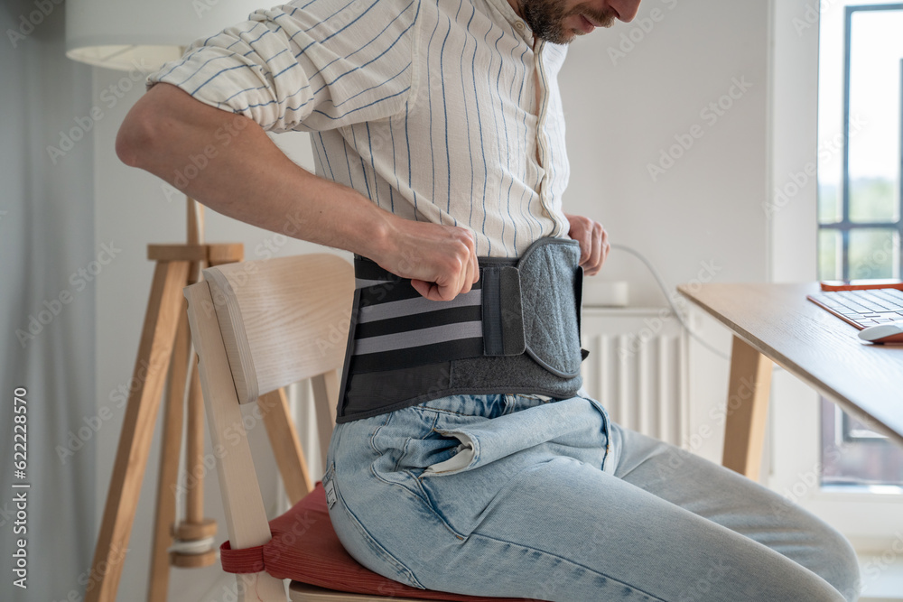 Fotografie Man sitting on chair wearing back brace to reduce hernias ...