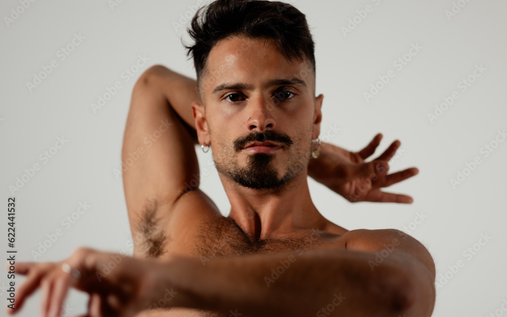 With one hand behind his head and another hand going towards the camera ...