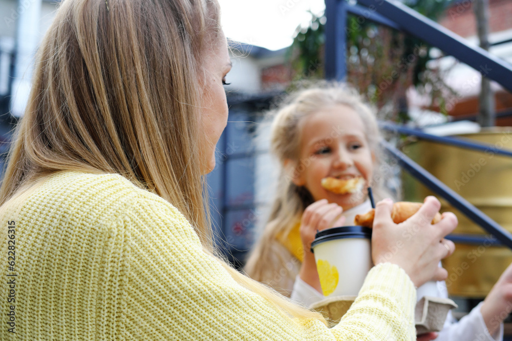 Mom and daughter are sitting on the steps with glasses of hot chocolate ...
