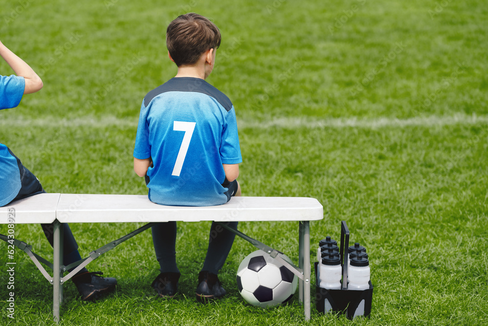 Schoolboy sitting on soccer bench. Young boy sitting on the substitute ...