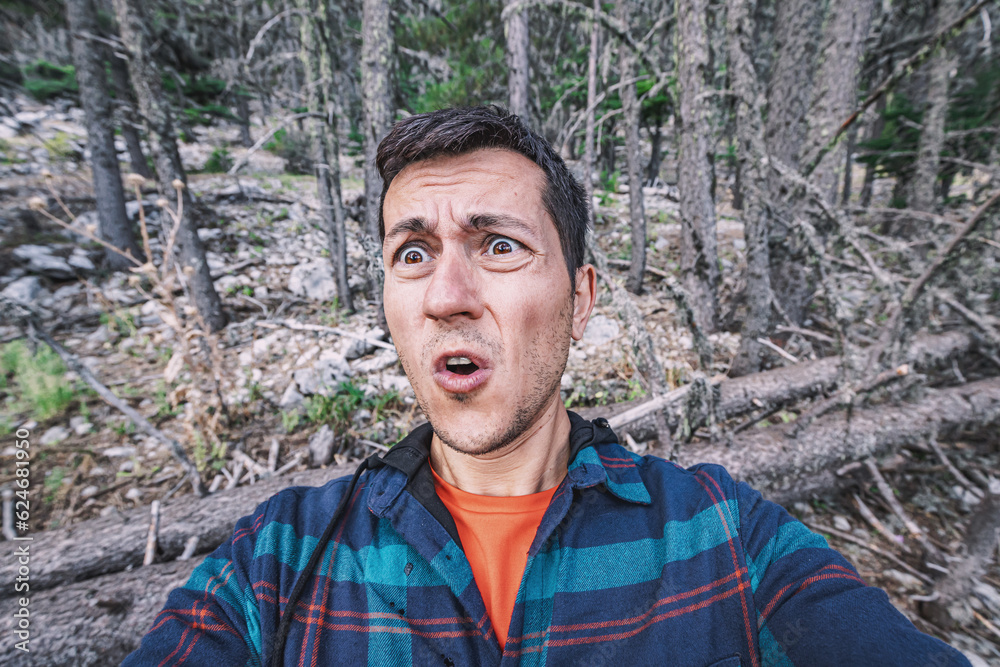 A frightened and lost male hiker looks around in the forest. The ...