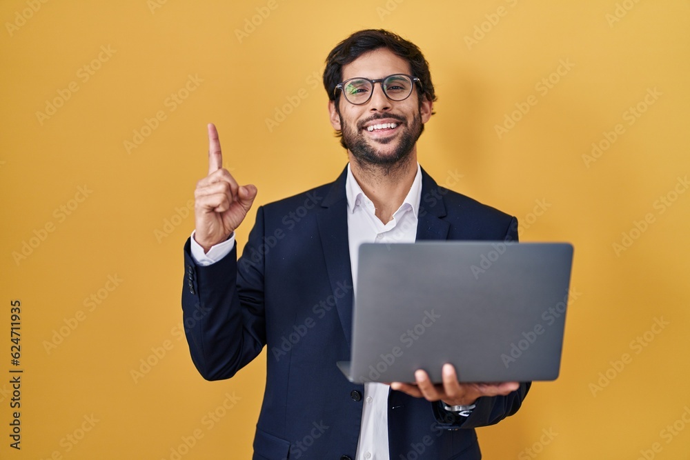Handsome latin man working using computer laptop pointing finger up ...