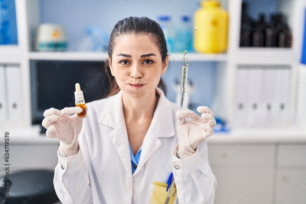 Young woman doing weed oil extraction at laboratory puffing cheeks with ...