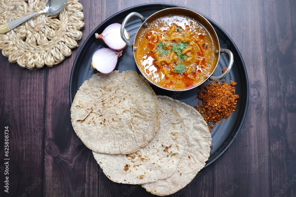 Traditional Sev bhaji or sev tamatar nu Shaak with Jowar Bhakri. Sev is ...