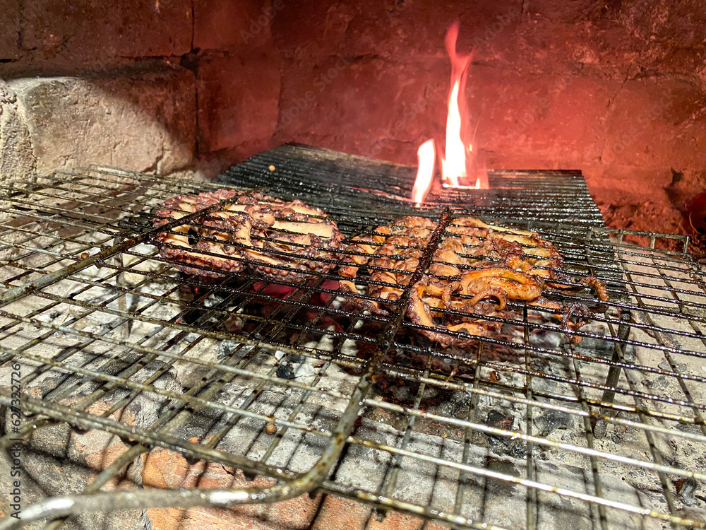 Octopuses fresh out of the Aegean Sea are cooked on the grill fire ...