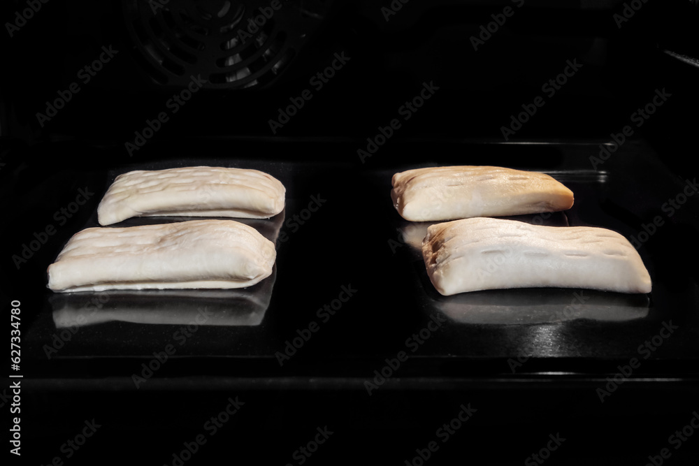 Four uncooked puff pastry buns with red strawberry jam on tray in ...