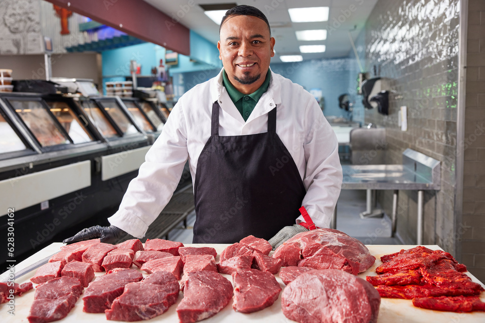 Smiling portrait of butcher wearing hair net behind counter of meat ...