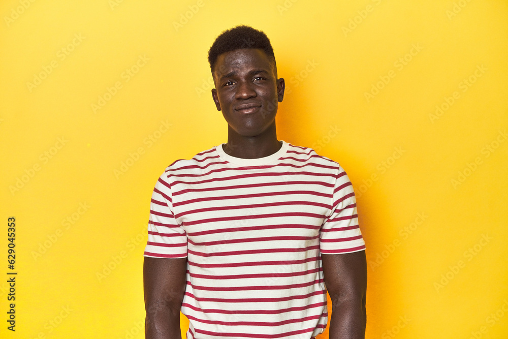 Stylish young African man on vibrant yellow studio background, sad ...