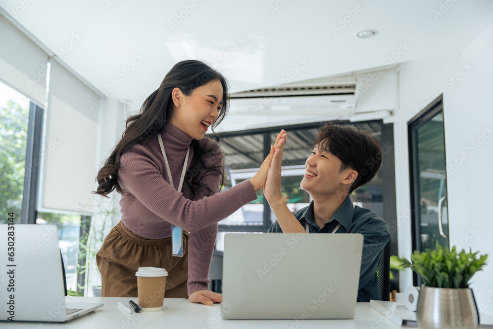 happy Asian female office worker gives high fives to a male colleague ...