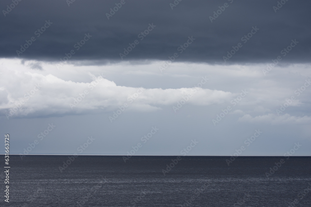 Layers of rainy, ominous, gloomy grey clouds overs a dark lake. Horizon ...