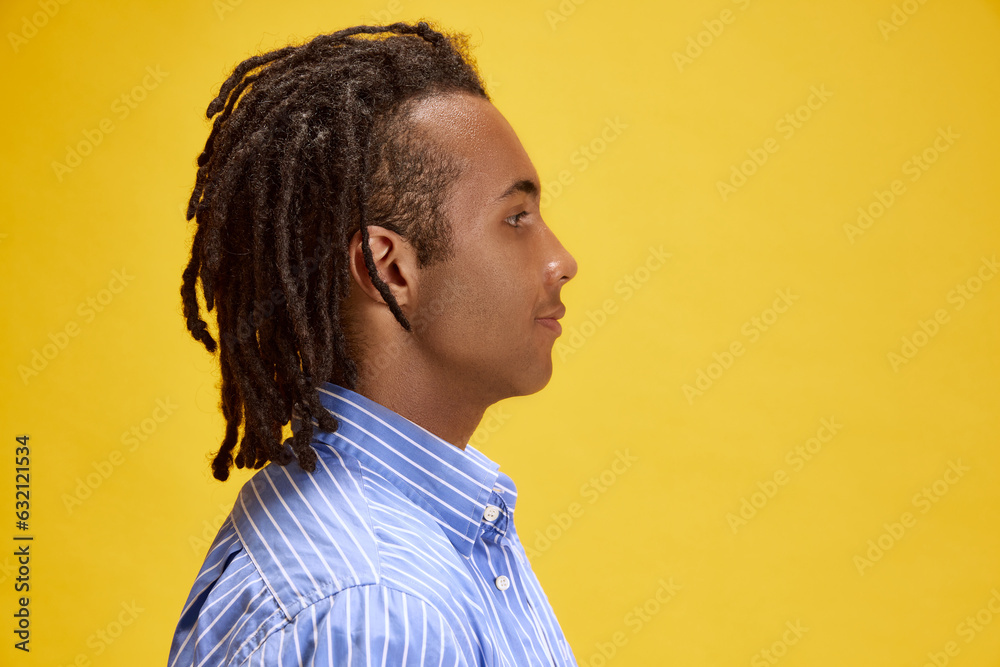 Side view portrait of young african man with dreads in shirt looking ...