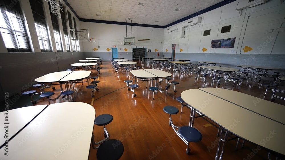 View to left showing dark and empty school cafeteria with tables and ...