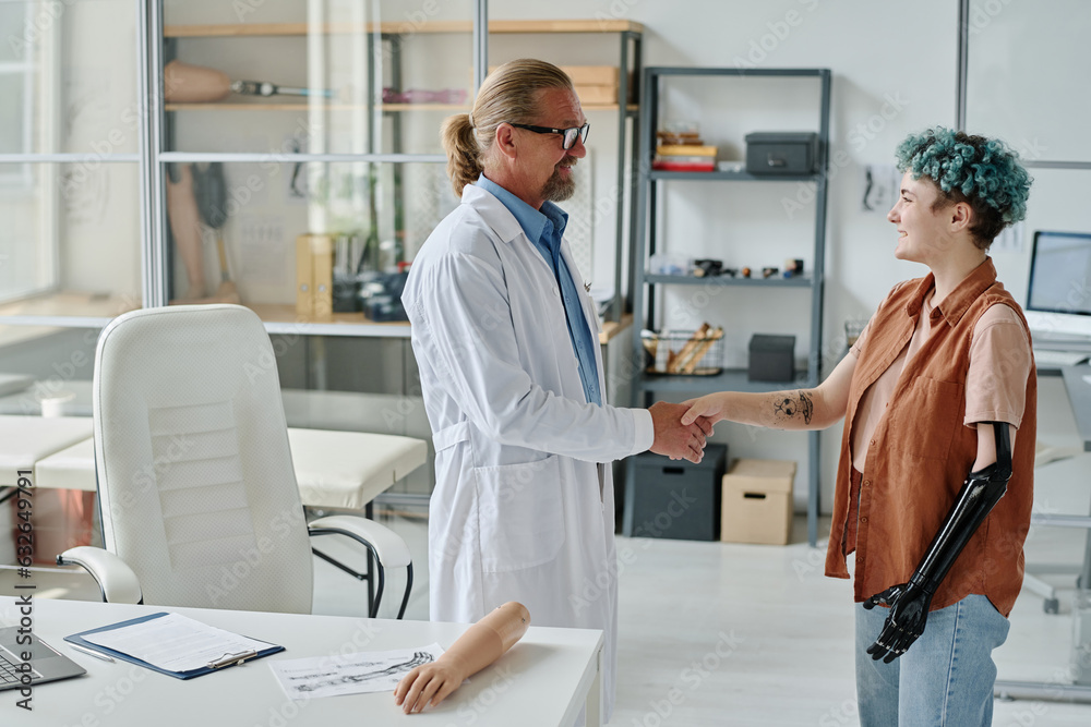 Side view portrait of senior doctor shaking hands with young woman with ...