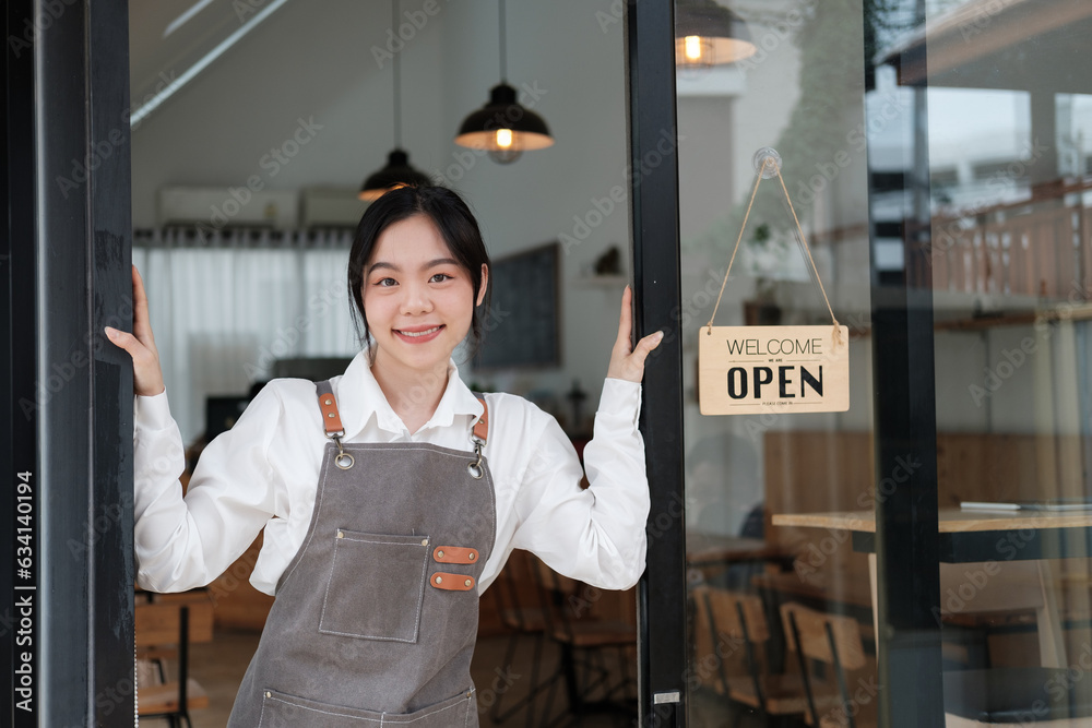 Beautiful and smiling barista with open sign in front of her cafe ...