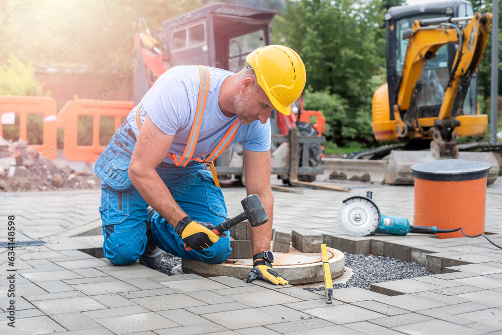 Laying interlocking paving. A worker is placing interlocking paving ...