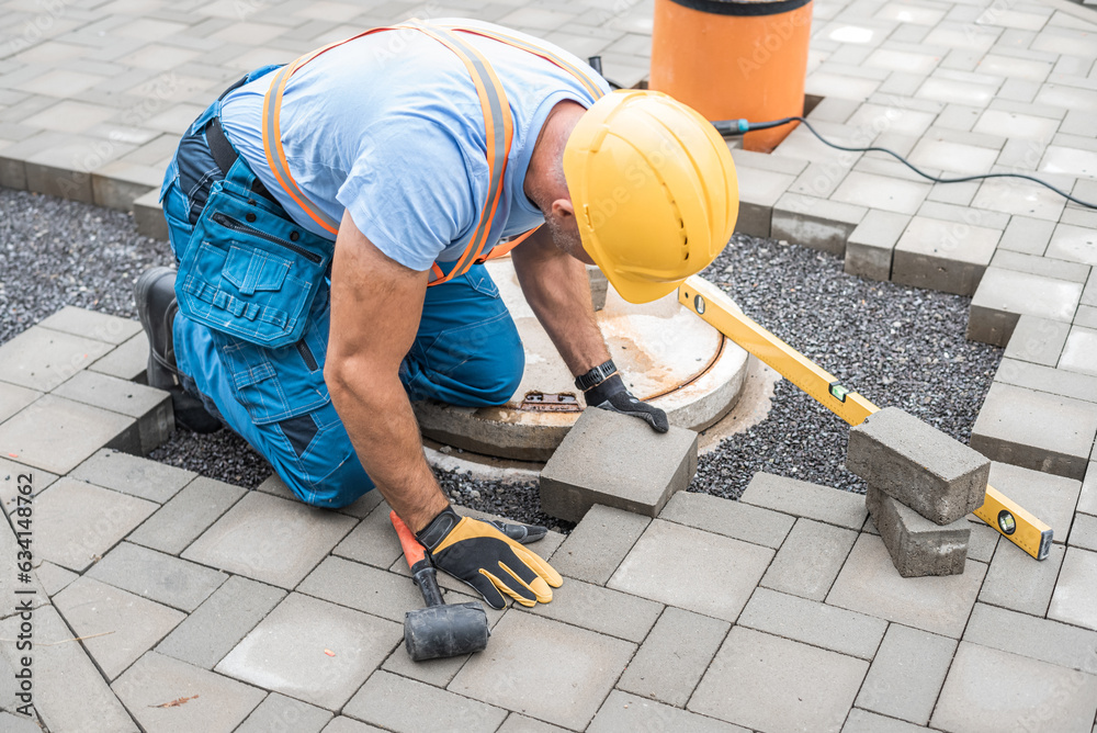 Laying interlocking paving. A worker is placing interlocking paving ...
