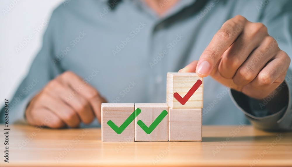 Wooden blocks checklist and green check mark icon with hand on table ...