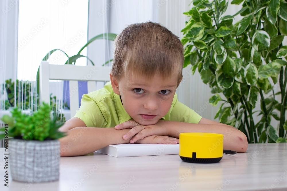 Child uses an intelligent speaker with voice control while doing ...