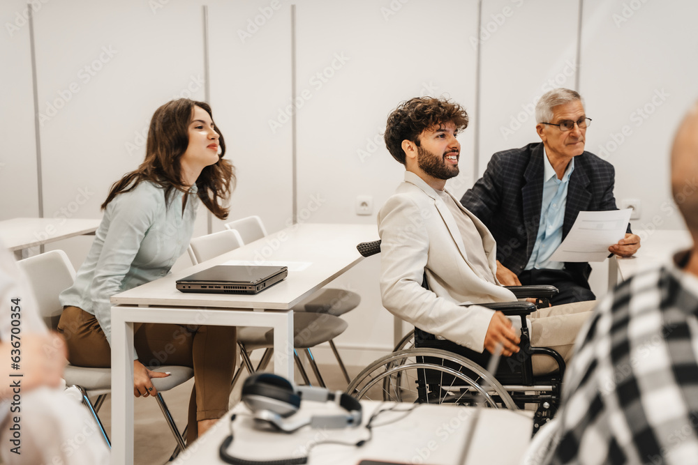 Handicapped male business person working with his colleagues at the ...