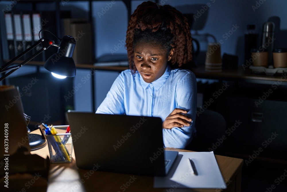 African woman working at the office at night afraid and shocked with ...