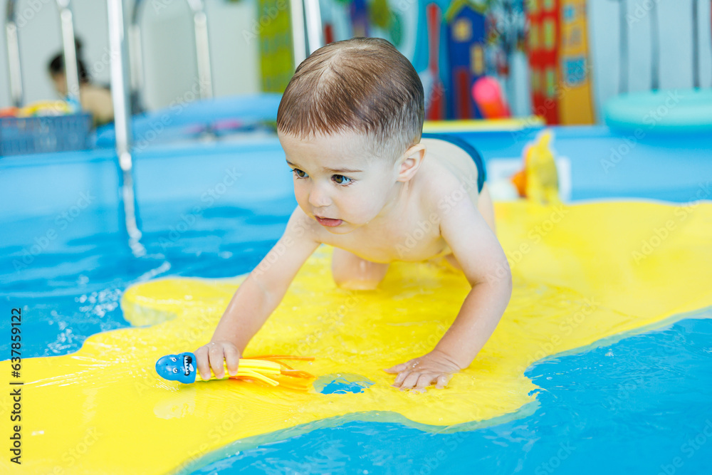 Development for babies. A little boy is learning to swim in the pool ...