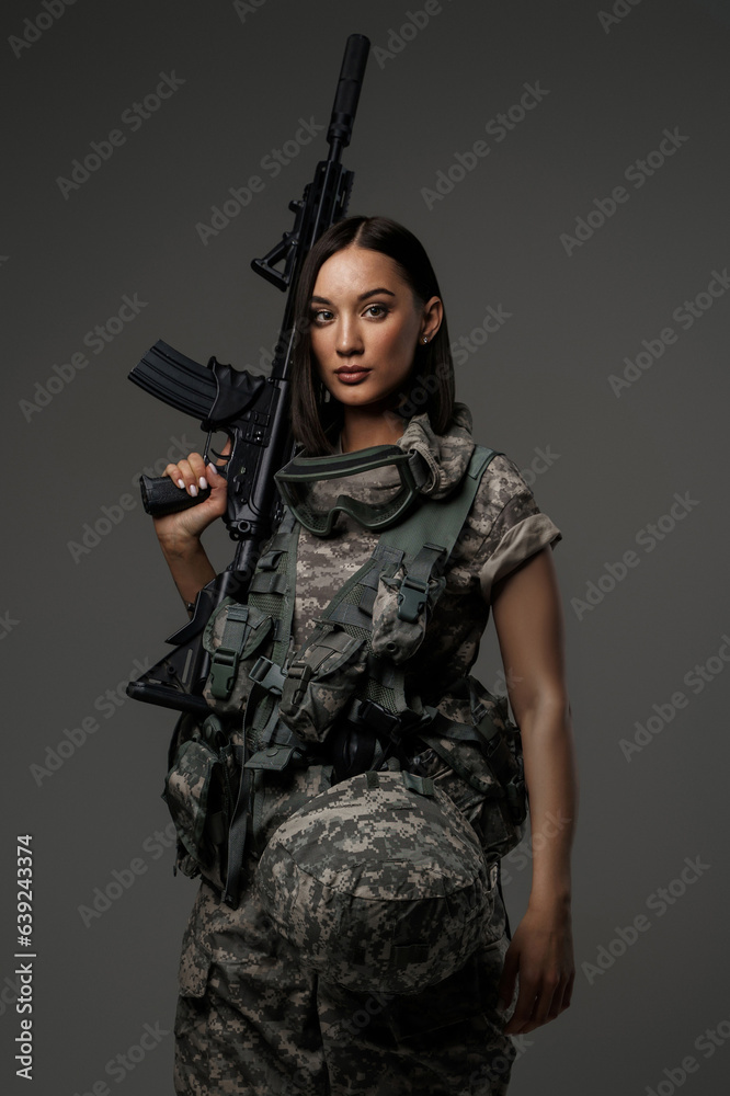 Beautiful female soldier in military uniform stands holding an ...