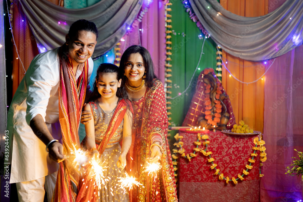 Indian family in ethnic wear celebrating Diwali with firecrackers at ...