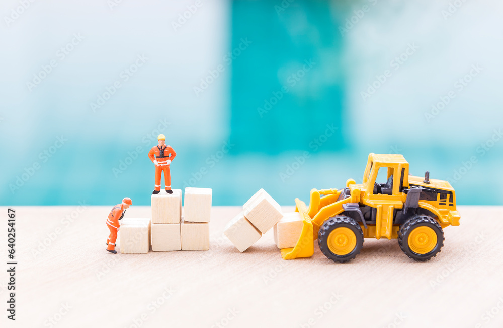 Miniature worker in safety suite with front loader truck and wooden ...