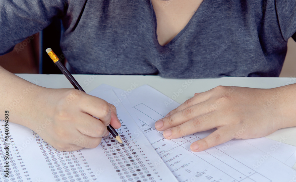 Students hand holding pencil writing selected choice on answer sheets ...