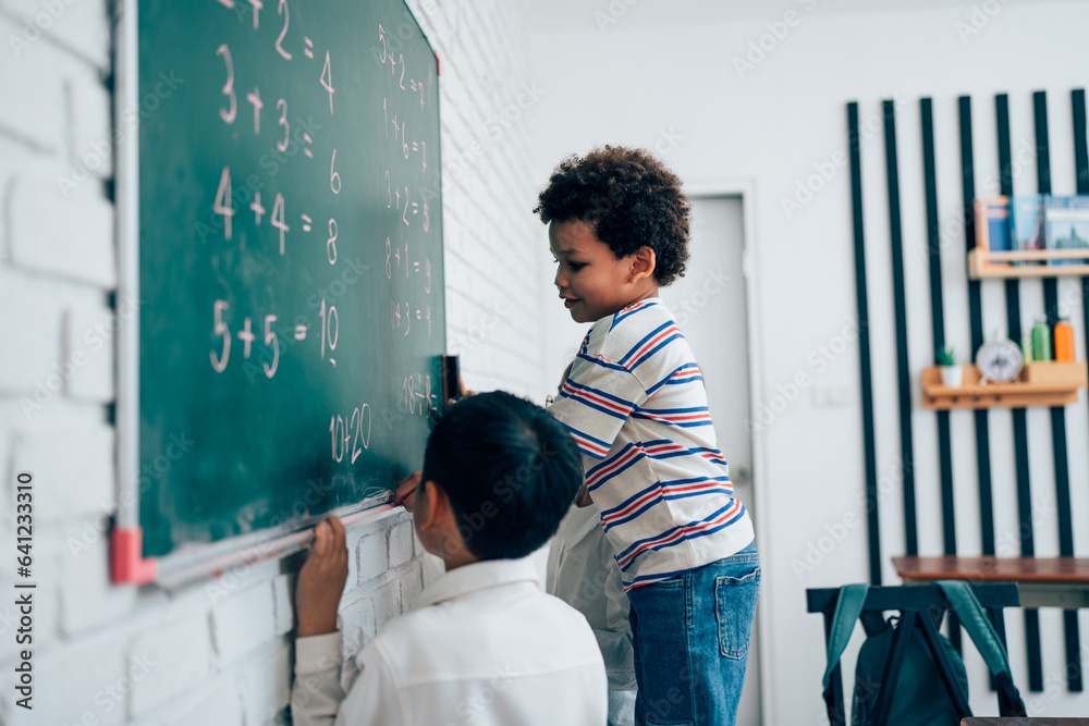 Group of little child standing at chalkboard and writing math formula ...