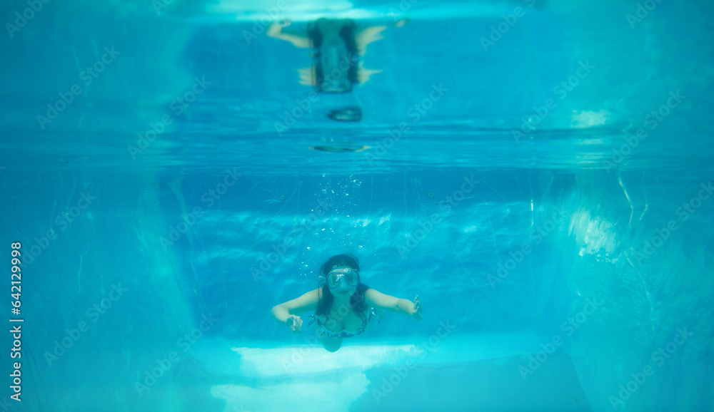 young woman swimming underwater in a personal pool with loose hair with ...