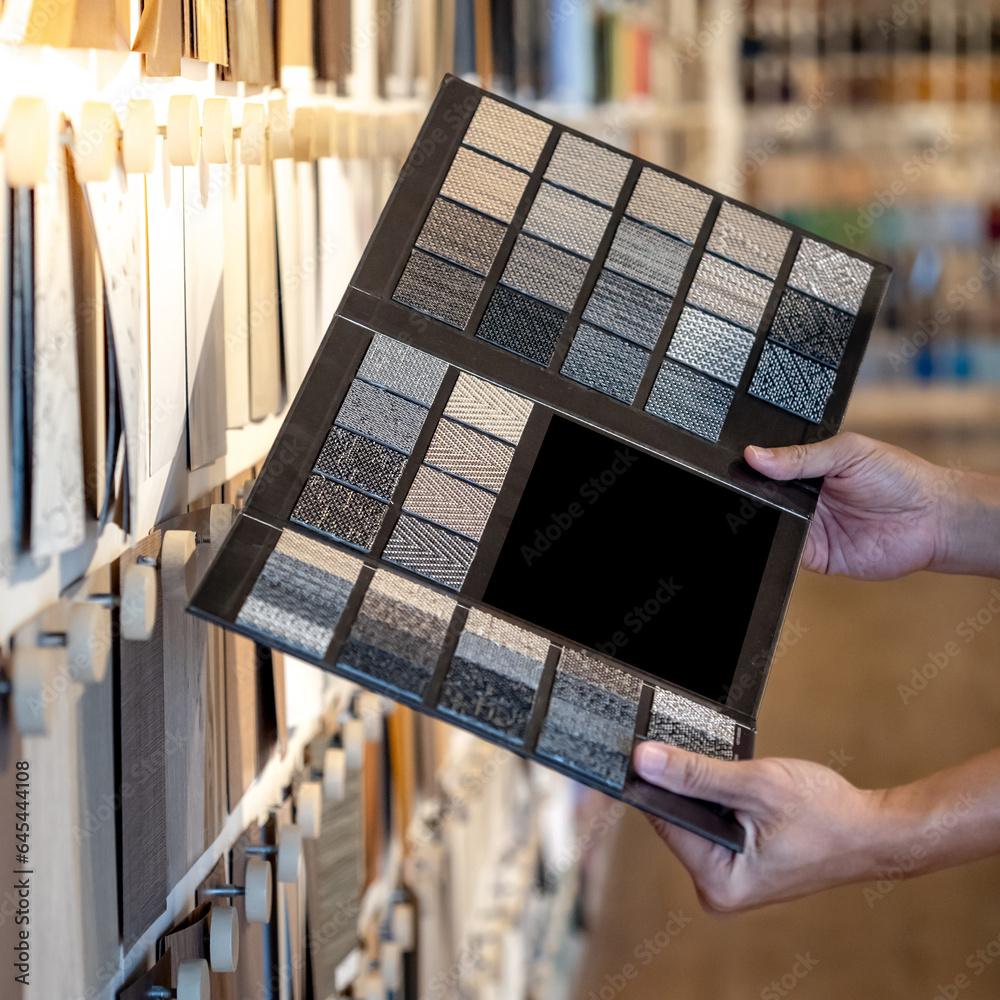 Designer hand holding fabric tile carpet samples catalog in material ...