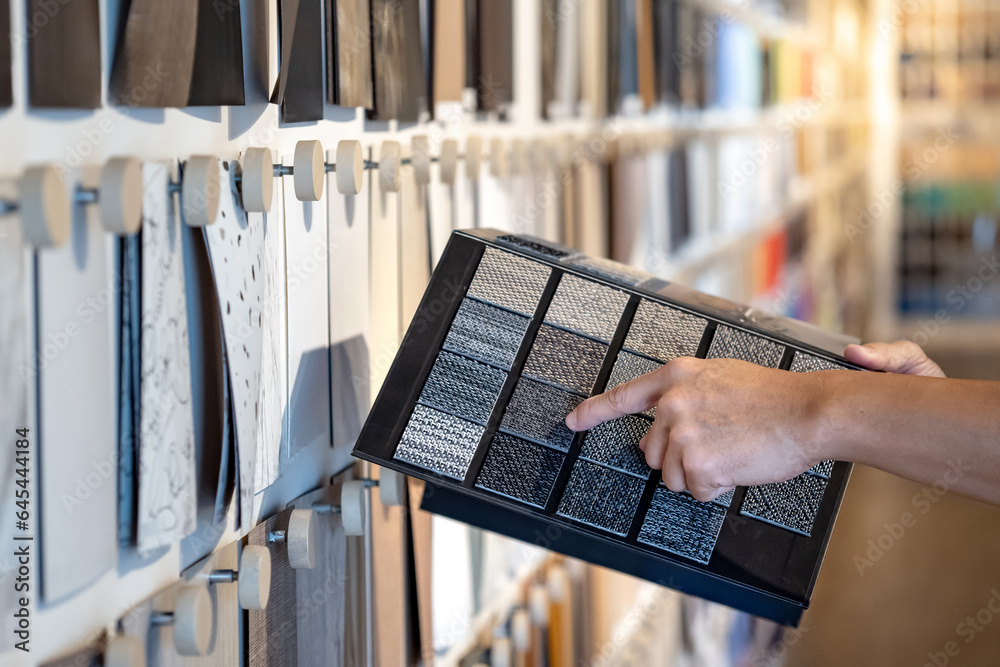 Designer hand pointing on fabric tile carpet samples catalog in ...