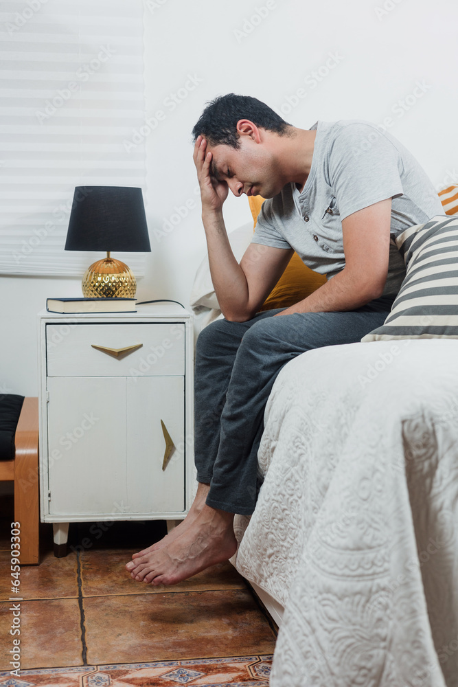 Lonely latin man feeling depressed and stressed sitting head in hands in bed at bedroom in ...