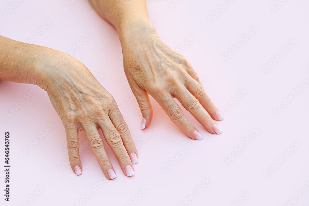 Hands with natural manicure of a elderly woman on a pink background ...