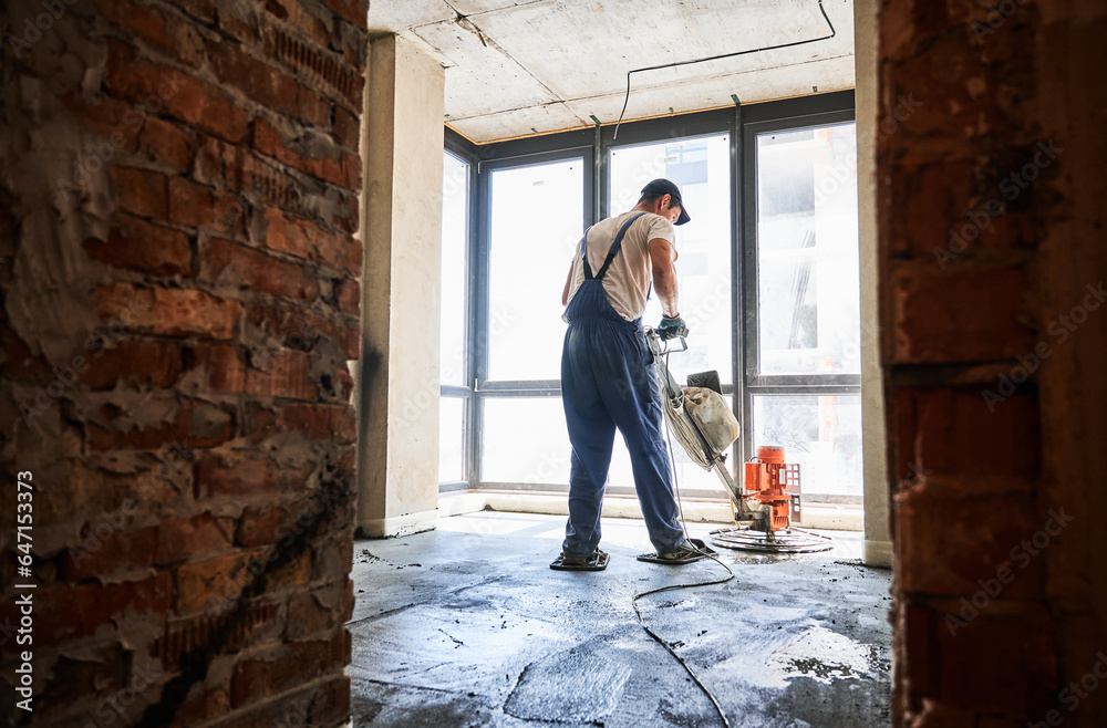 Man finishing concrete surface with floor screed grinder machine in ...