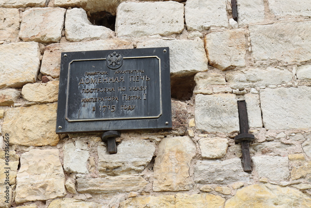 Foto de Stock Board on the wall of a sandstone blast furnace ...