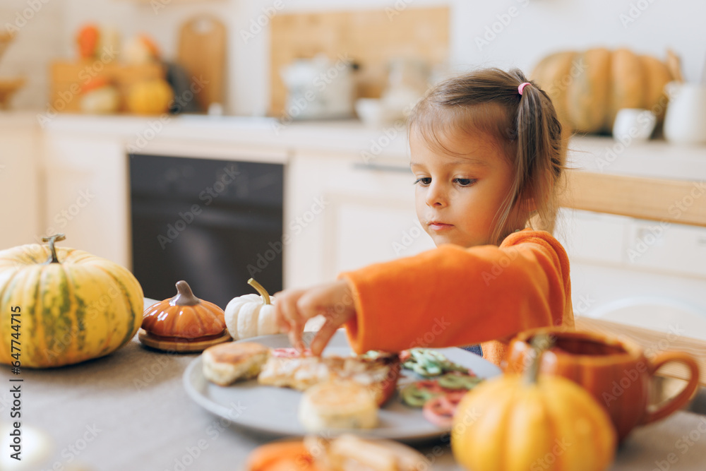 Happy Halloween! Little cute girl eating cookies in the kitchen ...