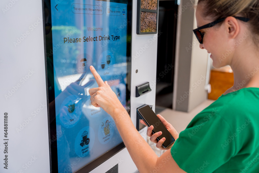 Young woman paying for coffee at vending machine using contactless ...