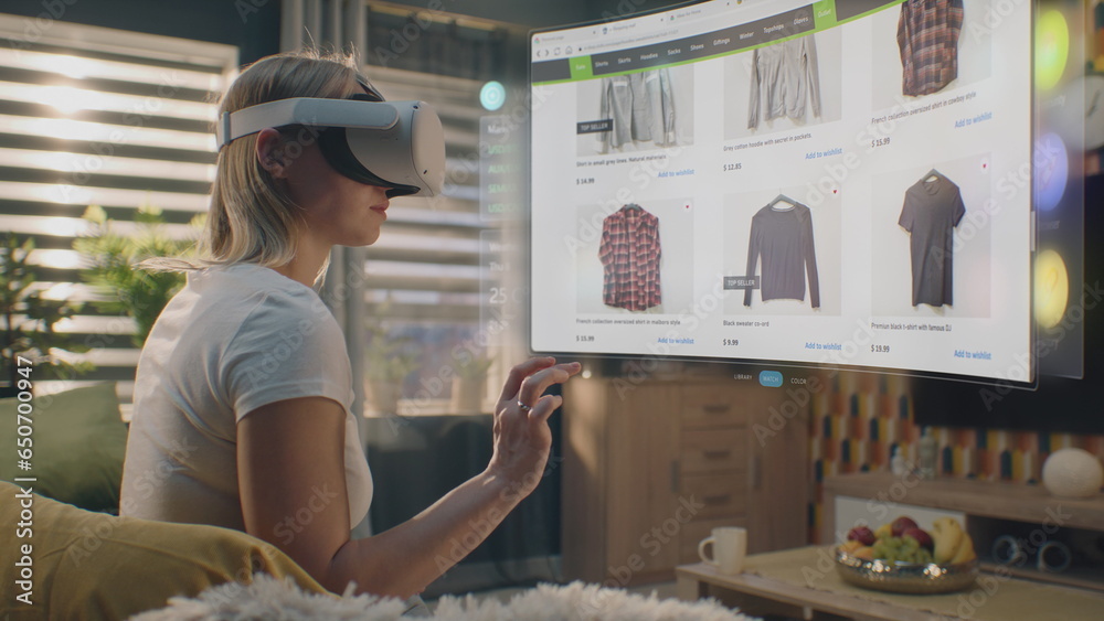 Woman in VR headset chooses clothes in online store chilling at home ...